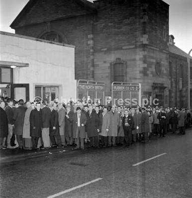 23461187-Employees of the North British Rubber Company queue for their ...