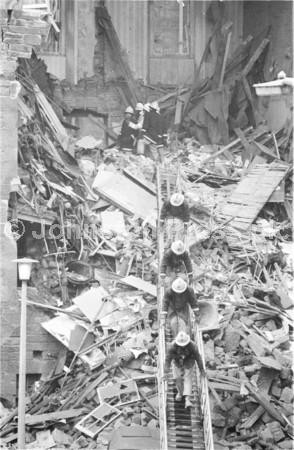 22703016-Firemen sift through the rubble, removing personal belongings ...