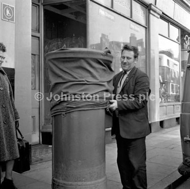 20235564-A Royal Mail postman takes the cover off a Post box after the ...