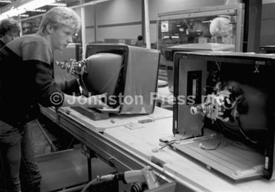 20378093-A factory worker puts a cathode ray tube into television sets ...