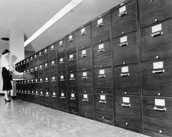 Side profile of a businesswoman searching for files in a filing cabinet ...
