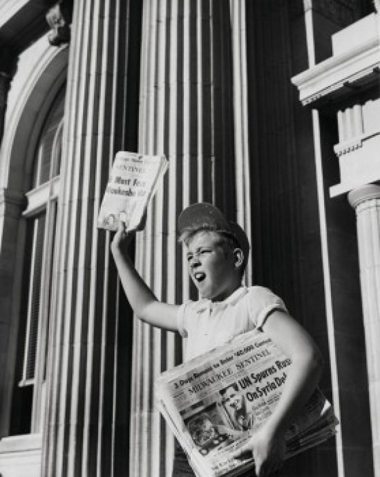 Boy selling newspaper in front of a building Poster Print - Item ...