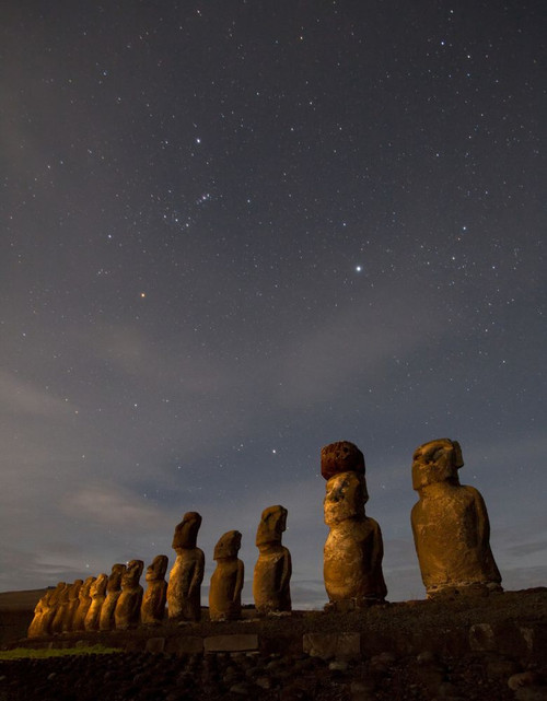 Moai stand at night illuminated beneath a sky full of stars on Easter ...